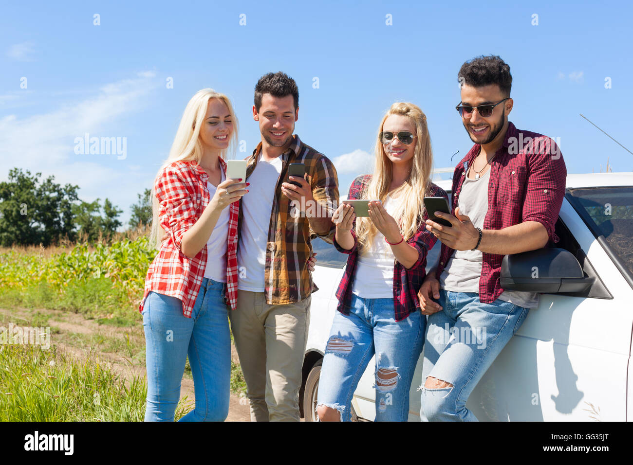 Friends using smart phone chatting outdoor countryside people messaging ...