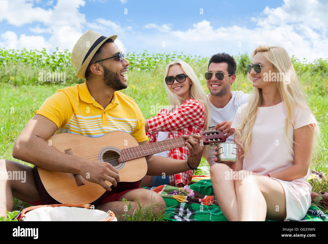 Young people listening guy playing guitar group friends summer day ...