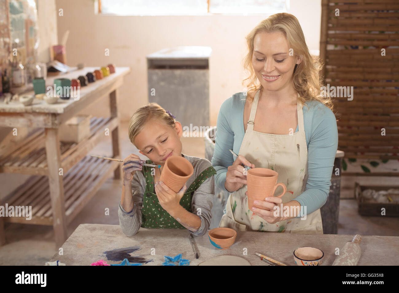 Female potter and girl painting in pottery workshop Stock Photo - Alamy