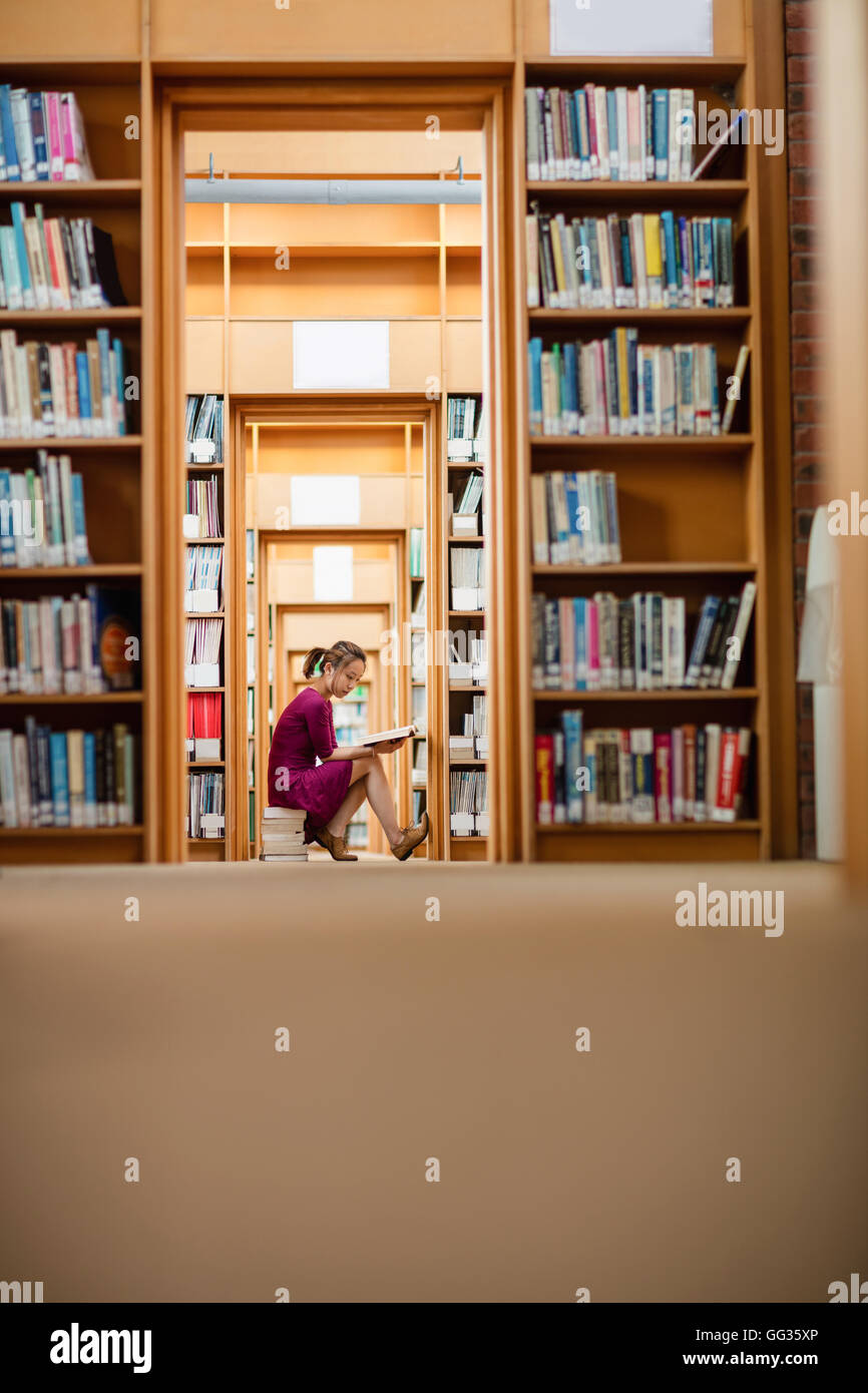 Young woman reading book in library Stock Photo - Alamy