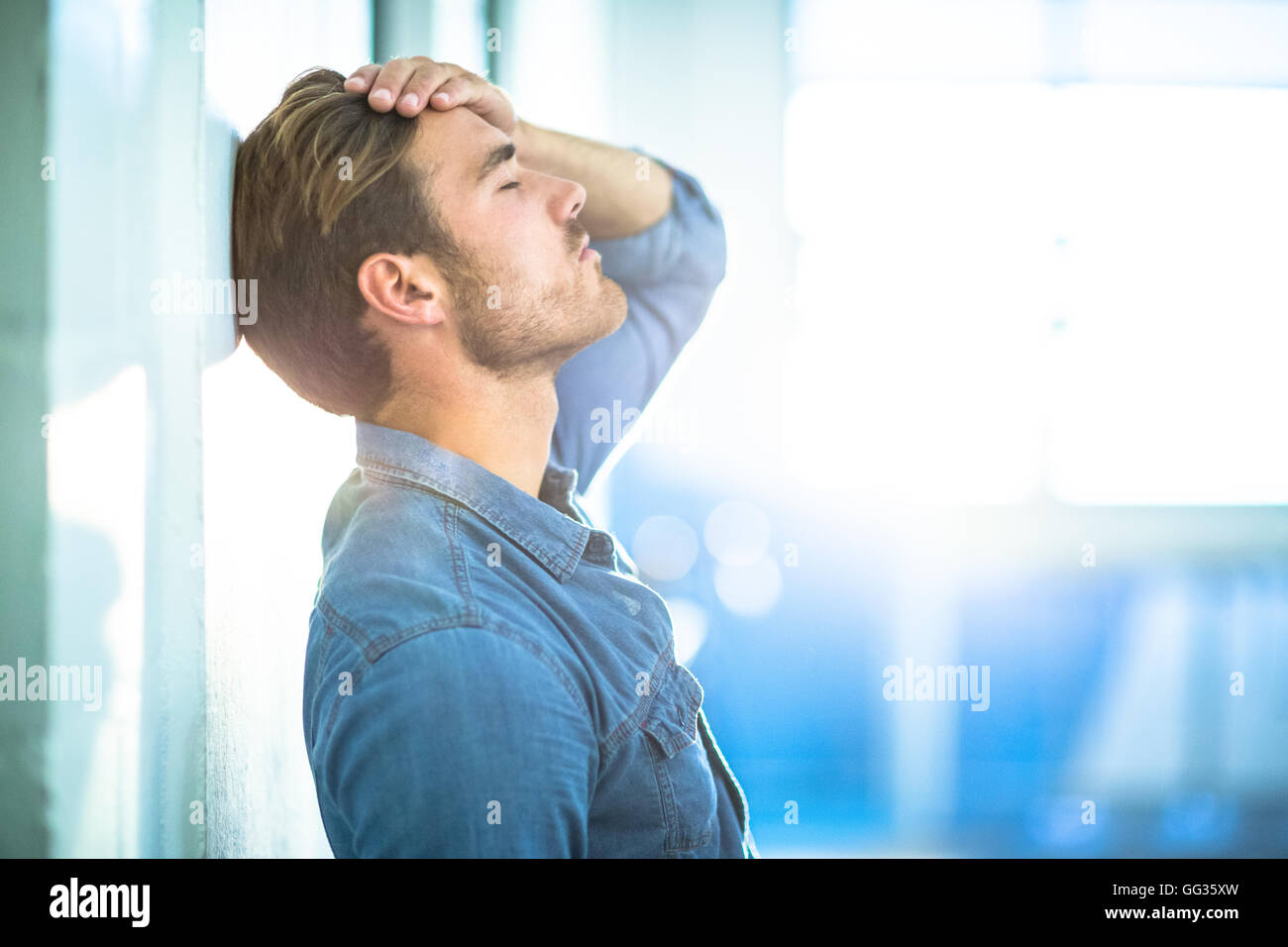 Tired businessman leaning on wall Stock Photo - Alamy