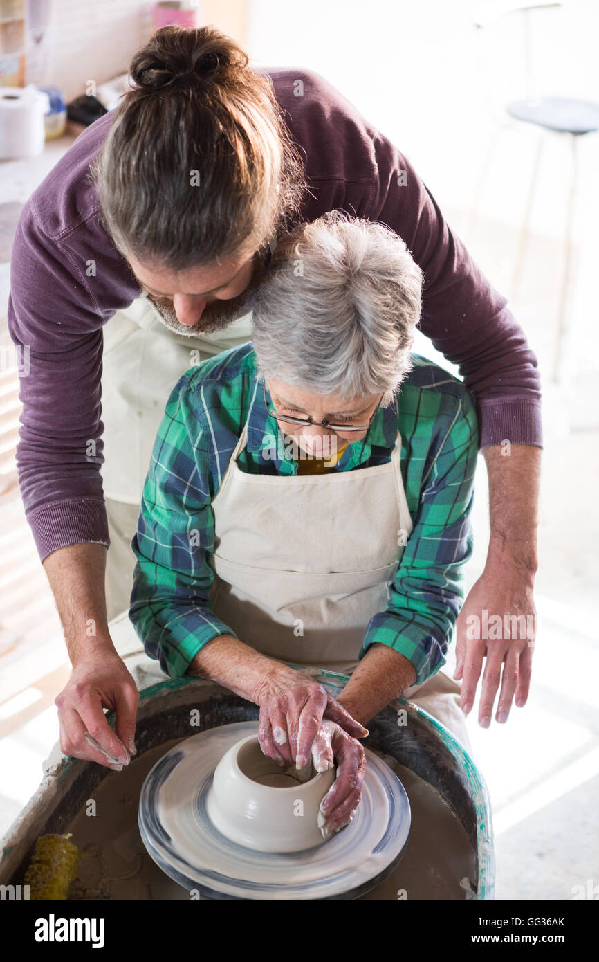 Male potter assisting female potter while making pot Stock Photo - Alamy