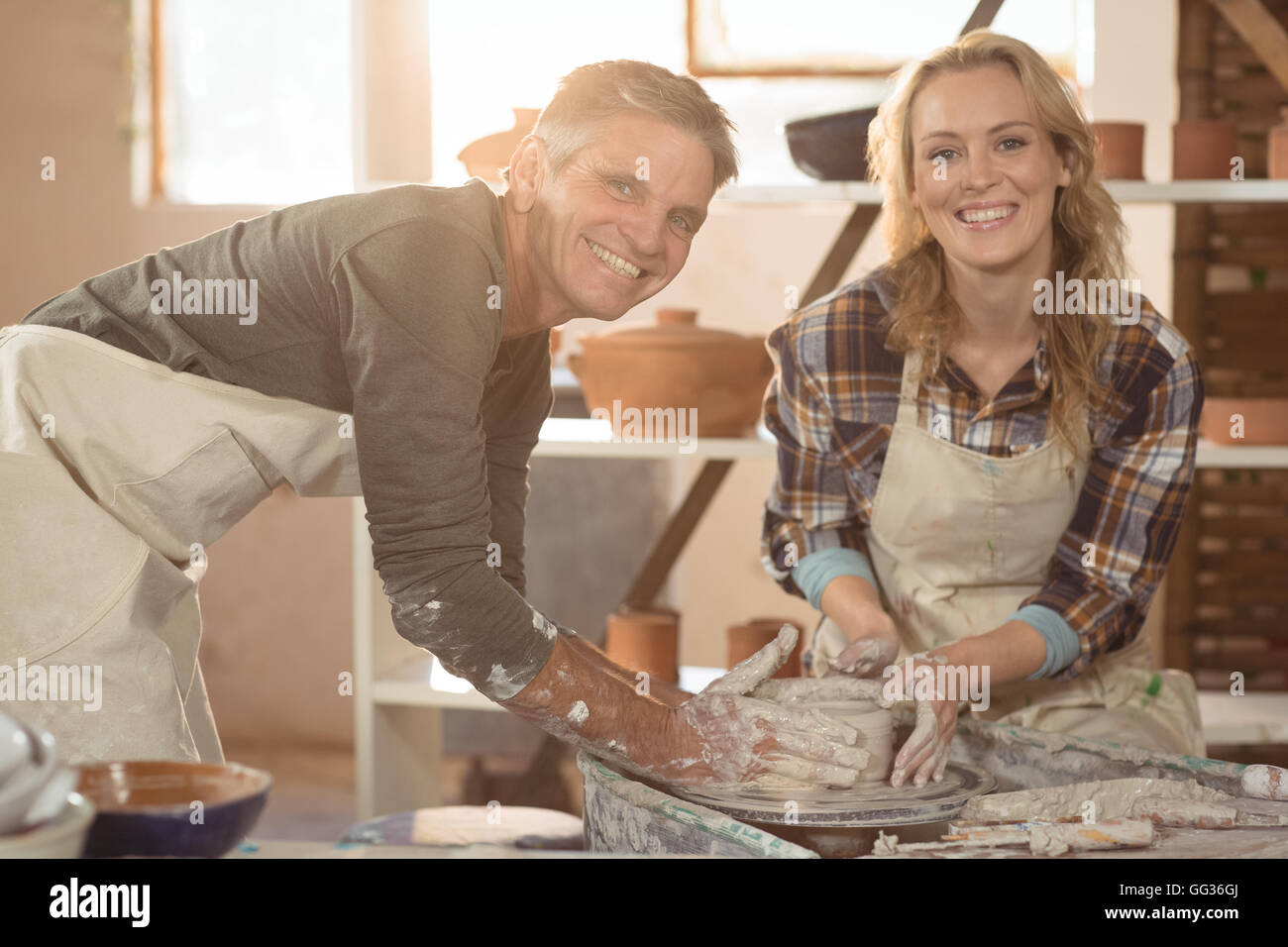 Male potter assisting female potter in pottery workshop Stock Photo - Alamy