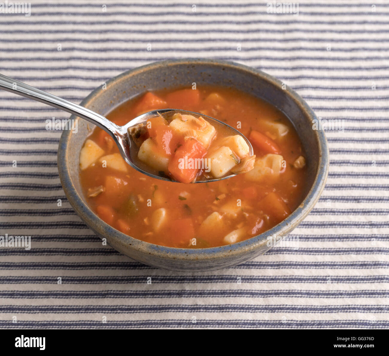 A serving of Manhattan style clam chowder in an old stoneware bowl with ...