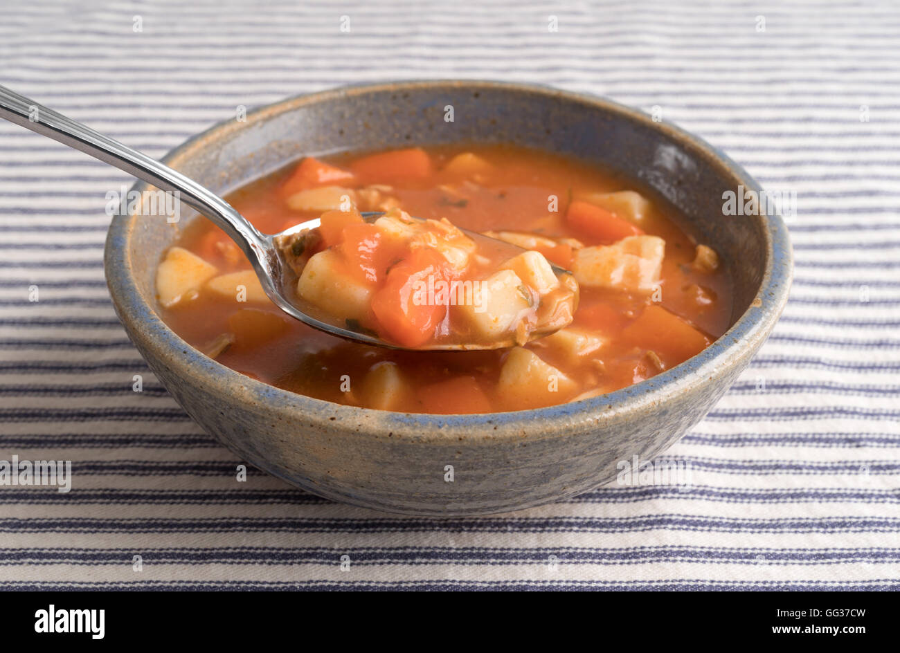 A serving of Manhattan style clam chowder in an old stoneware bowl with ...