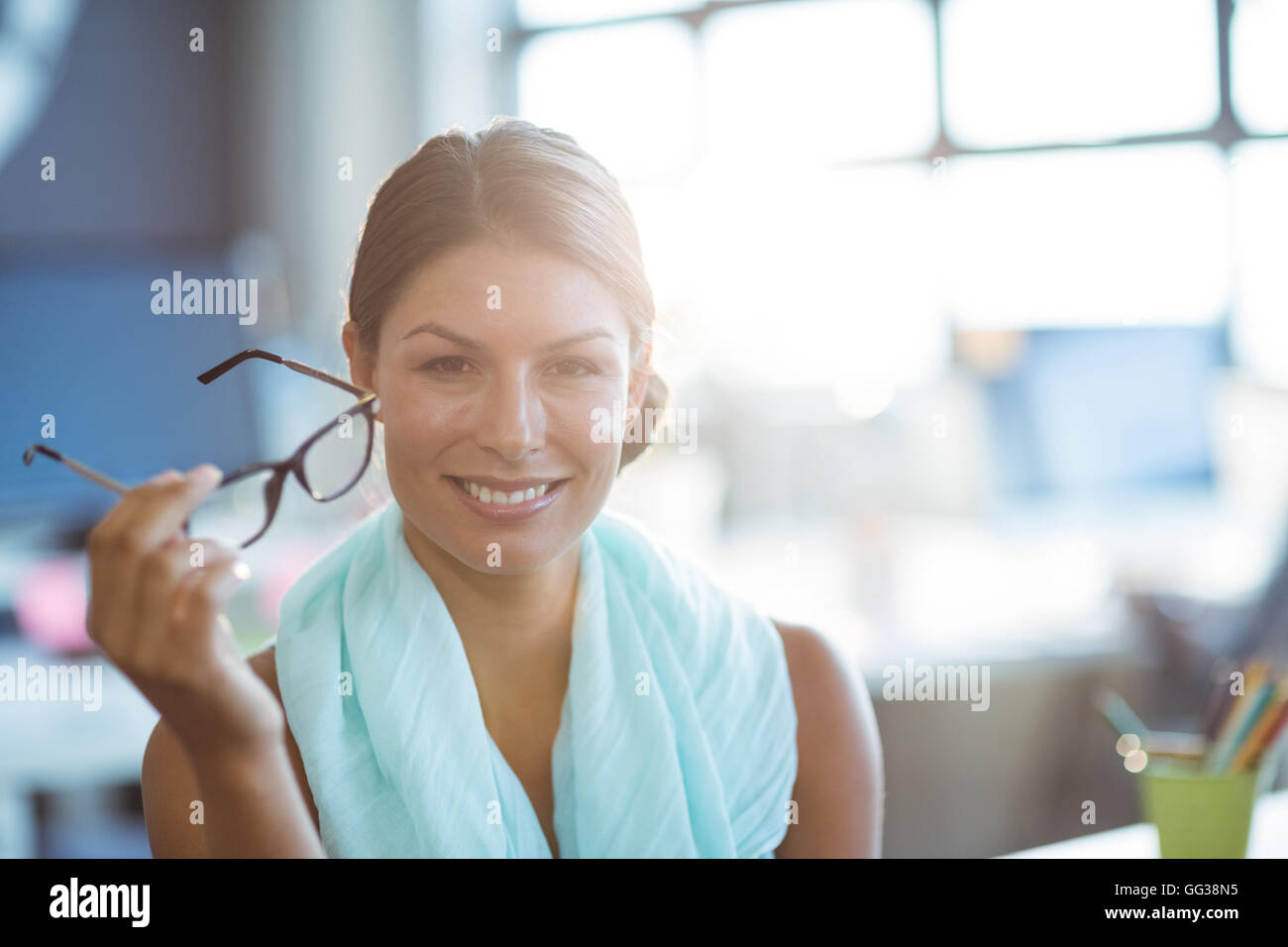 Business executive holding spectacles in office Stock Photo - Alamy