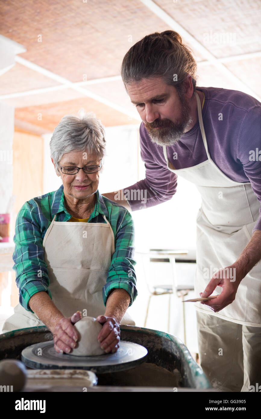 Male potter assisting female potter while making pot Stock Photo - Alamy