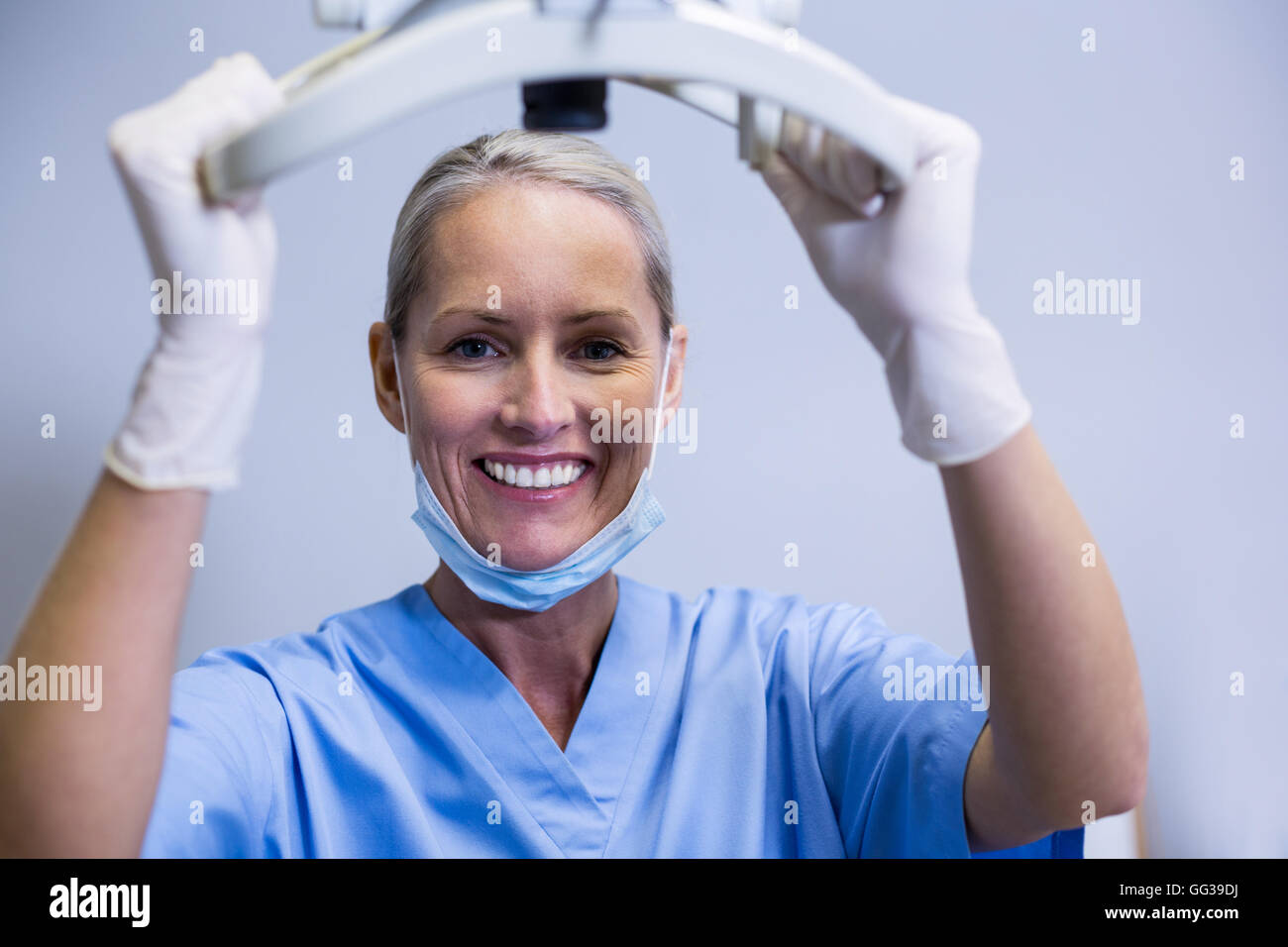 Smiling dental assistant adjusting light in clinic Stock Photo - Alamy