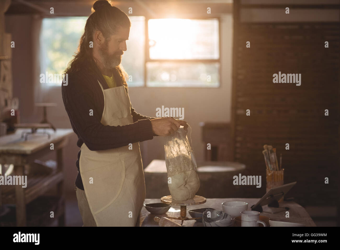 Male potter removing plastic cover from molding clay Stock Photo - Alamy