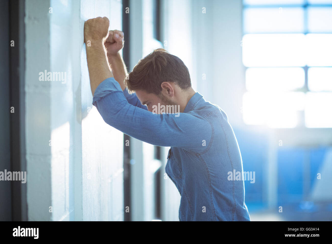 Tired businessman leaning on wall Stock Photo - Alamy