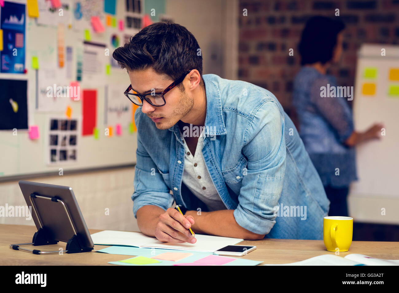 Business executive looking at digital tablet and taking notes in diary ...