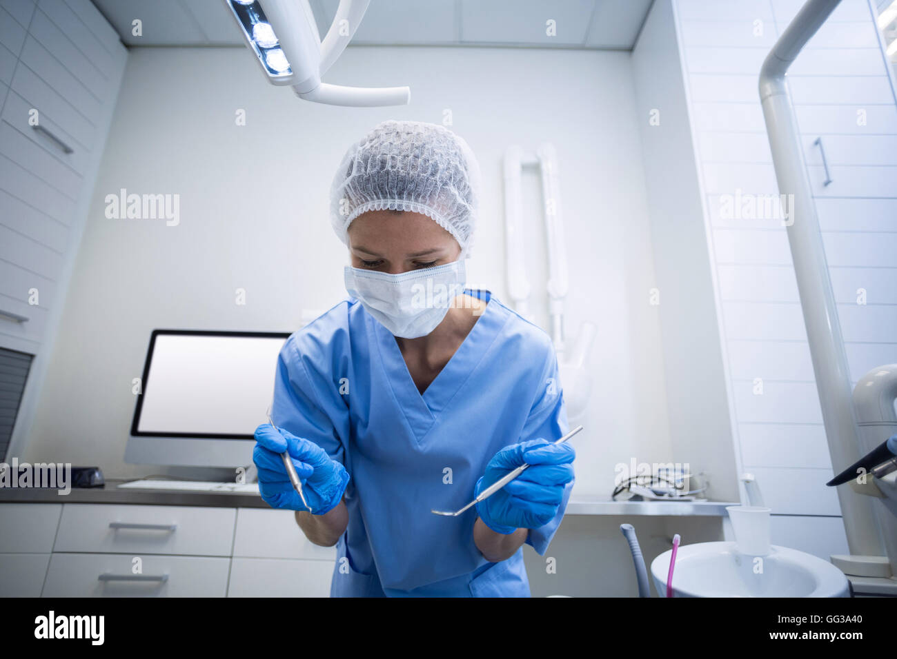 Dental assistant in surgical mask holding dental tools Stock Photo - Alamy