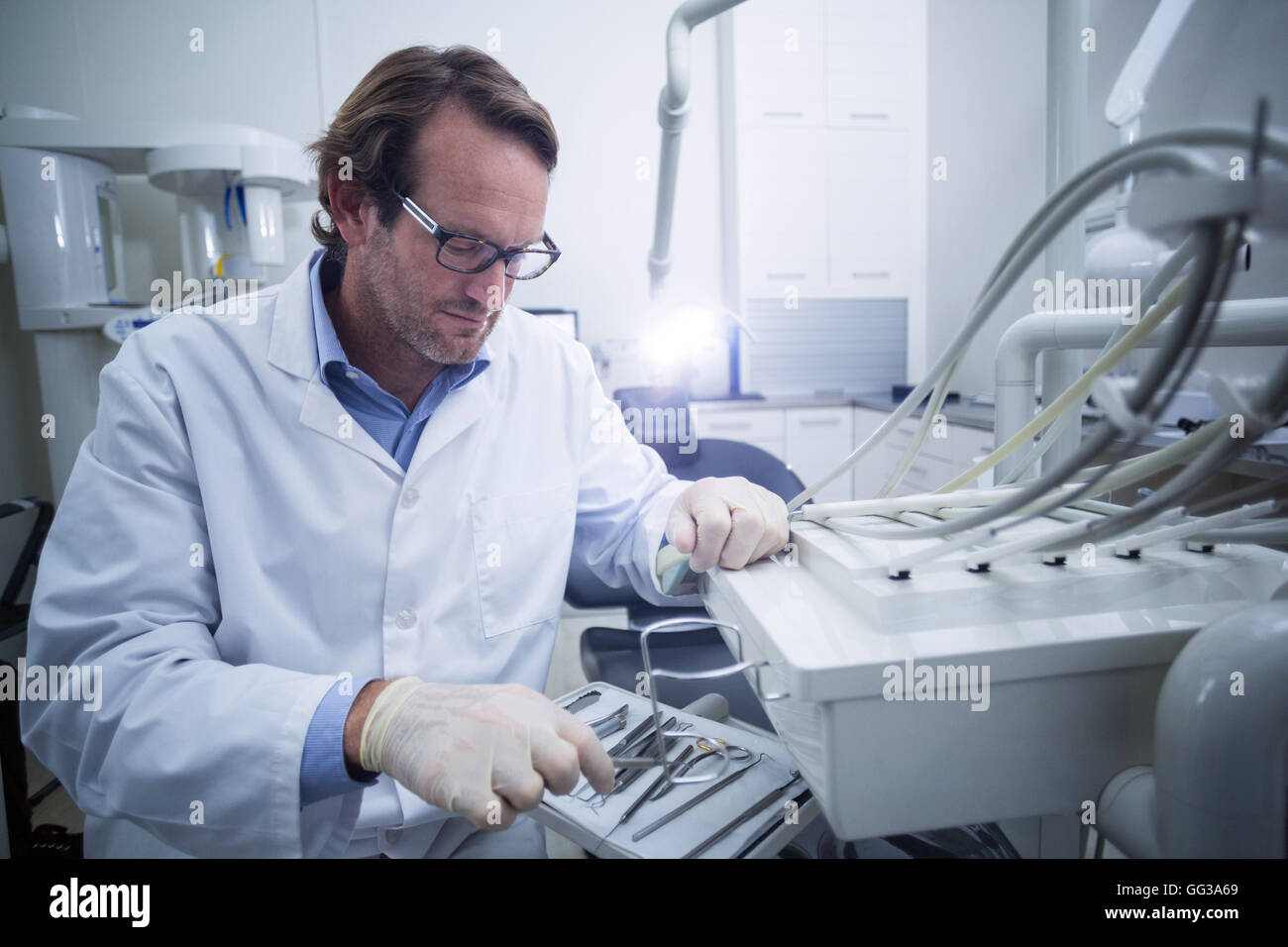 Dentist looking at dental tool Stock Photo - Alamy
