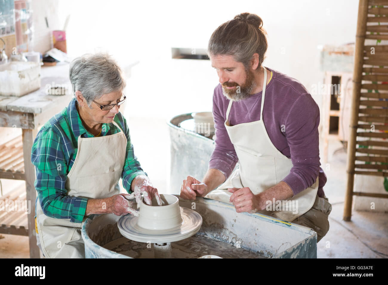Male potter assisting female potter while making pot Stock Photo - Alamy