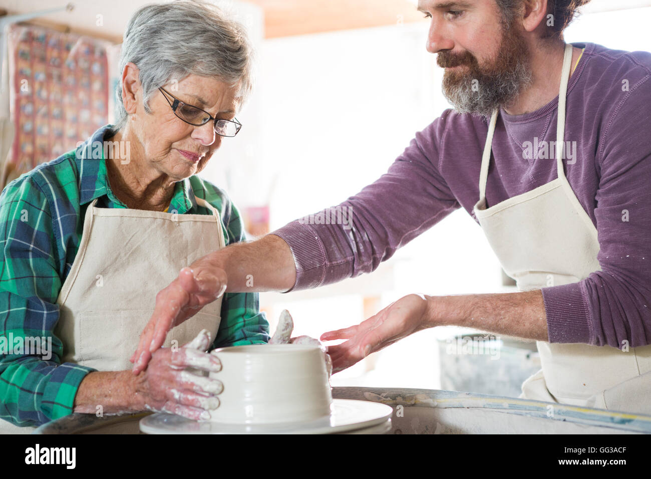 Male potter assisting female potter while making pot Stock Photo - Alamy