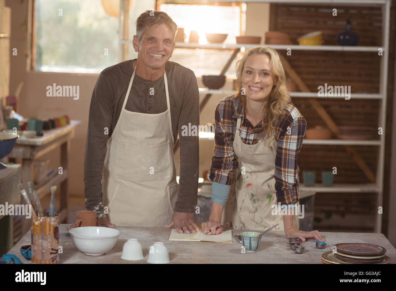 Smiling potters writing in book at pottery workshop Stock Photo - Alamy