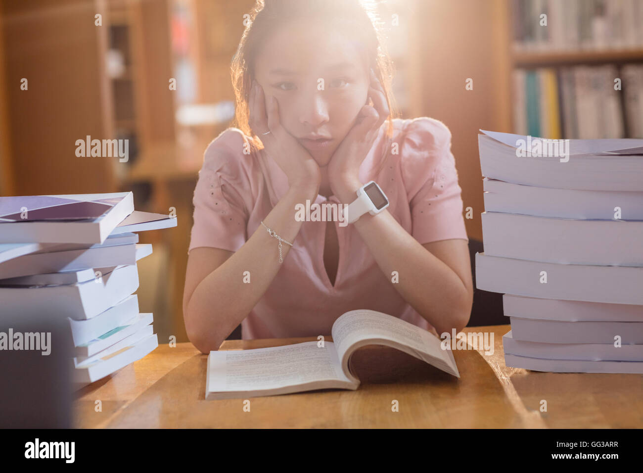 Sad young woman studying in library Stock Photo - Alamy