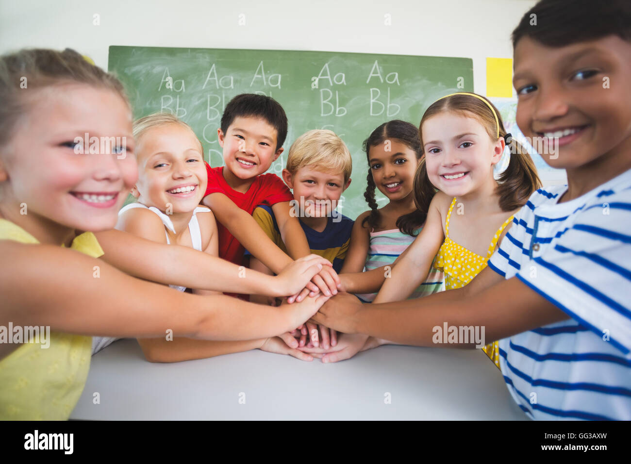 School kids stacking hands in classroom Stock Photo - Alamy