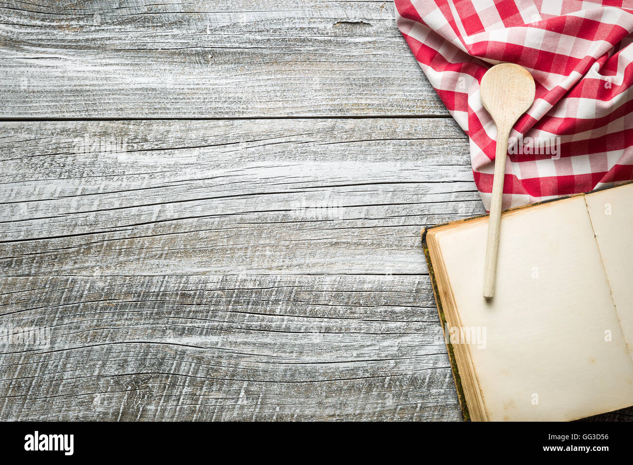 Cooking concept. Checkered napkin, wooden spoon and blank recipe book ...