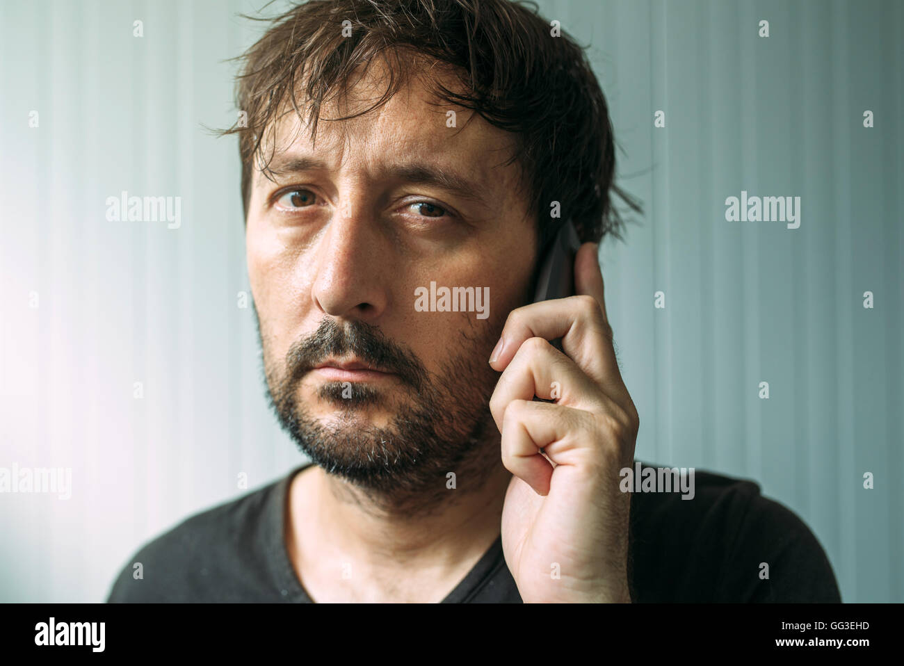 Tired adult man talking on mobile phone, studio indoors portrait Stock ...
