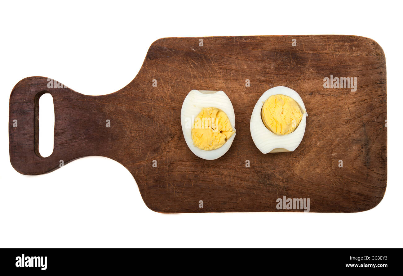 boiled egg split in two halves on a wooden board, all on a white ...