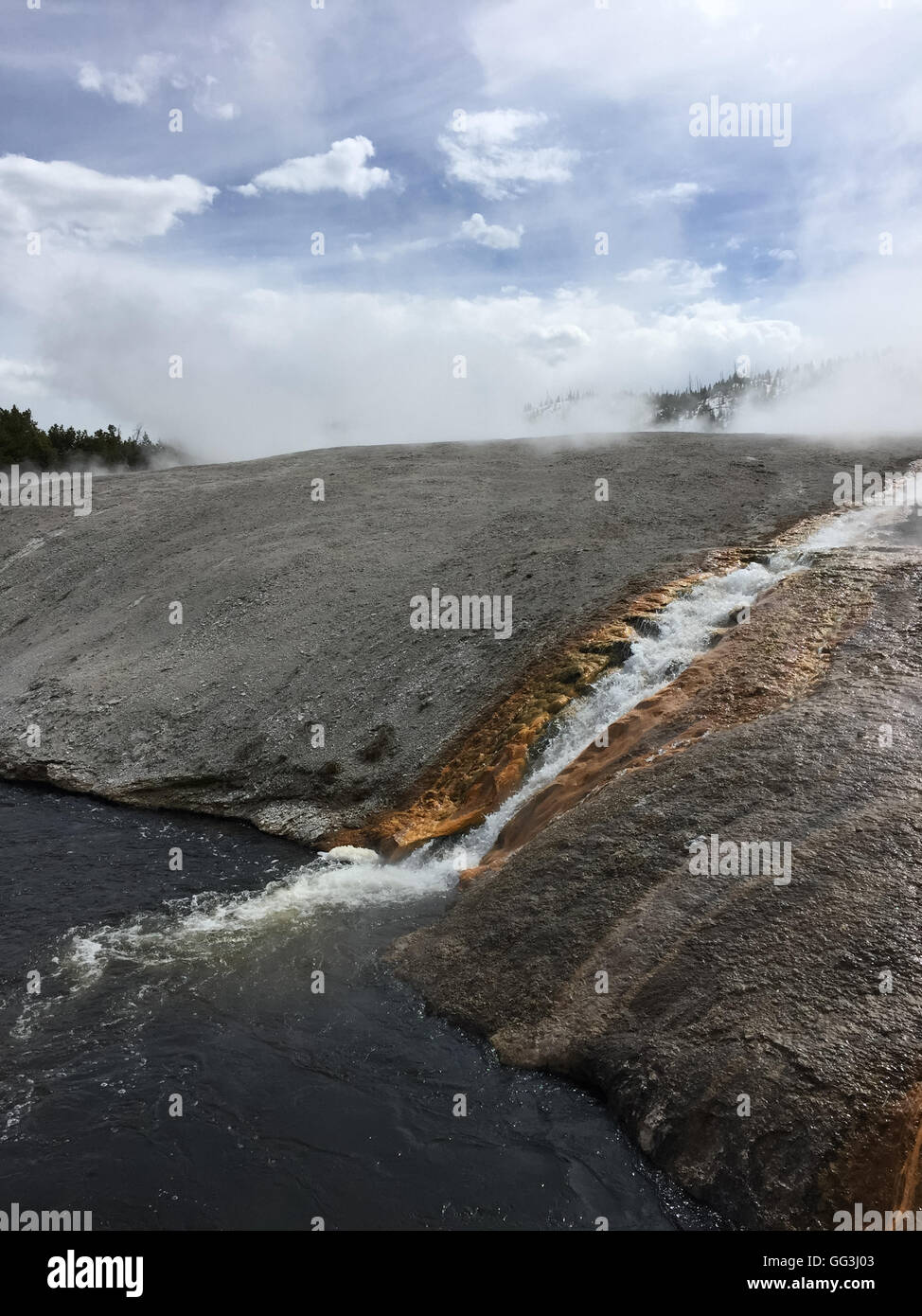 Hot water from a hot spring rushes down a slope into a stream Stock ...
