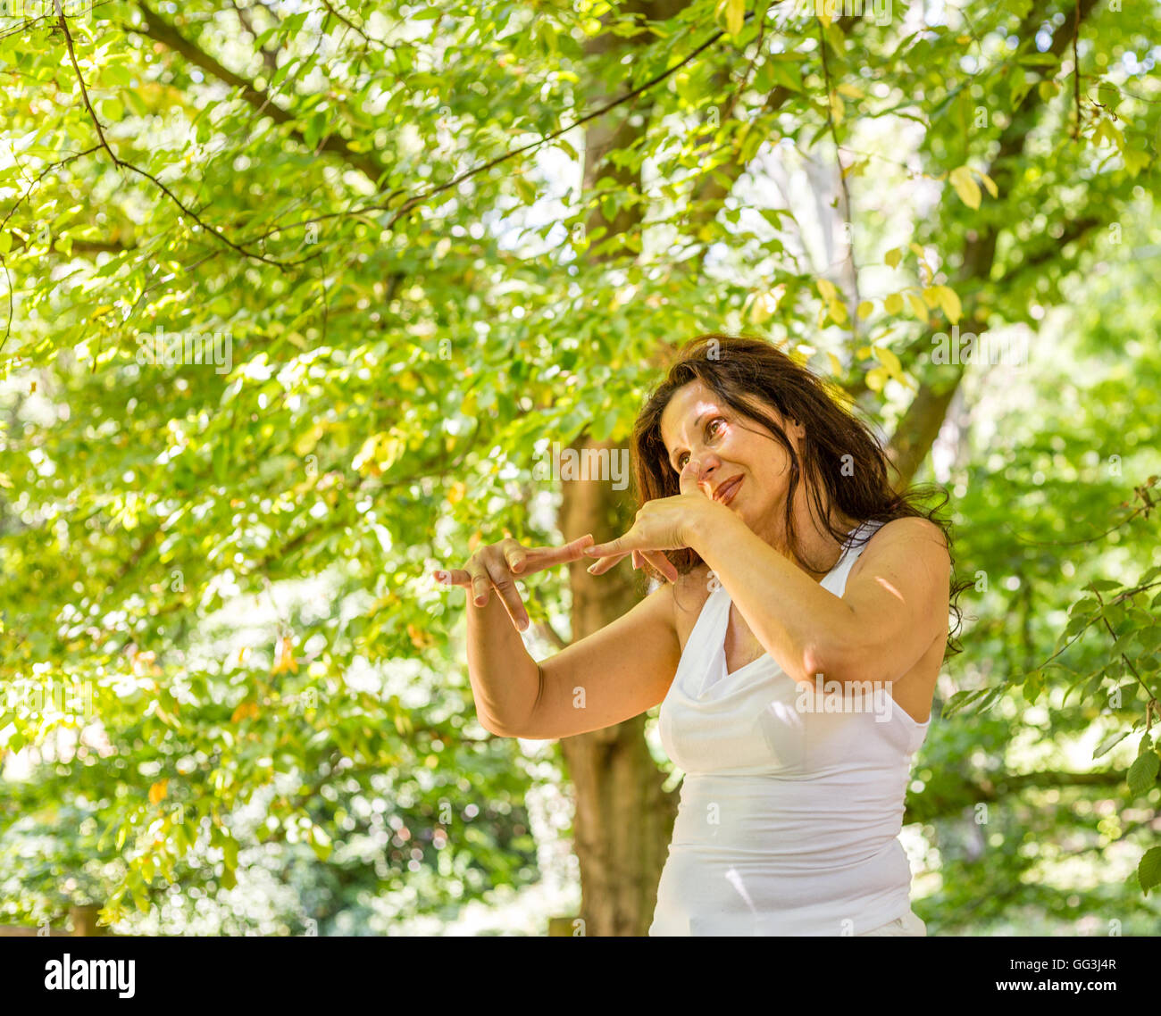 Sunny menopausal woman smiles thumbing her nose with hands Stock Photo ...