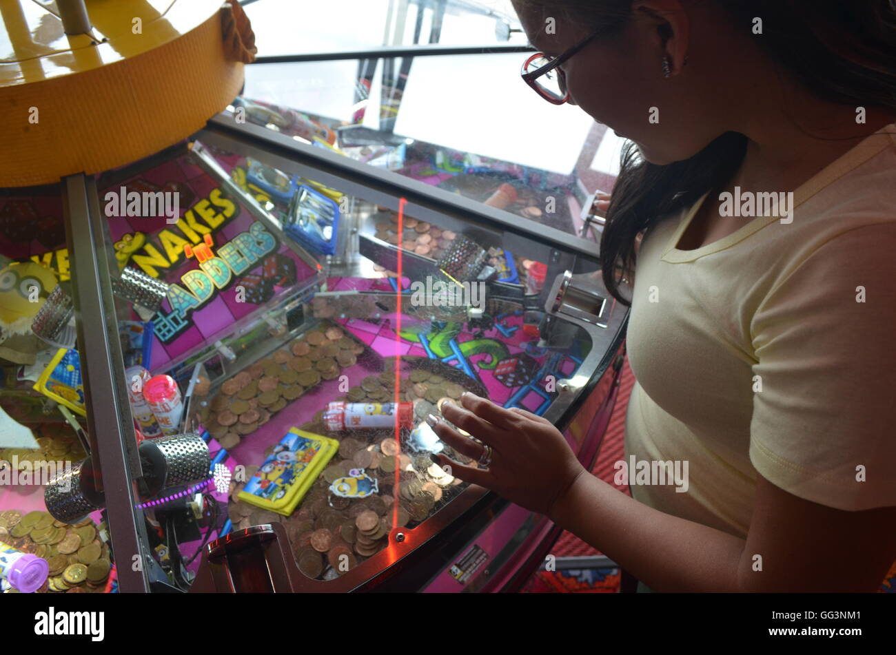 A girl playing on the coin slot machines in a seaside funfair in Whitby ...