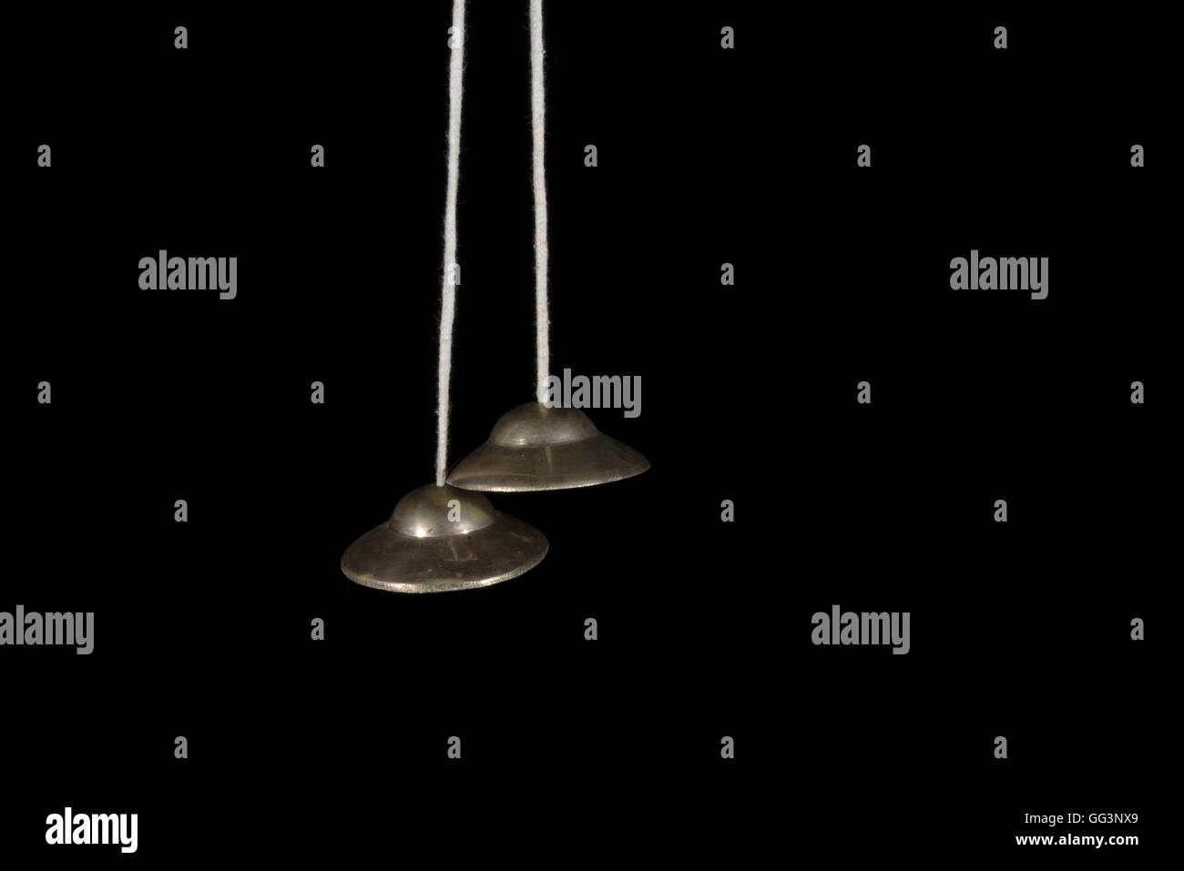Hindu cymbals hanging from a white rope on black background Stock Photo ...