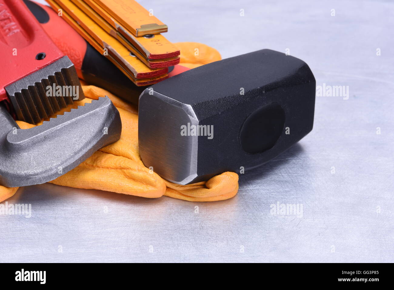 Closeup hand working tools pipe wrench and hammer on metal surface ...