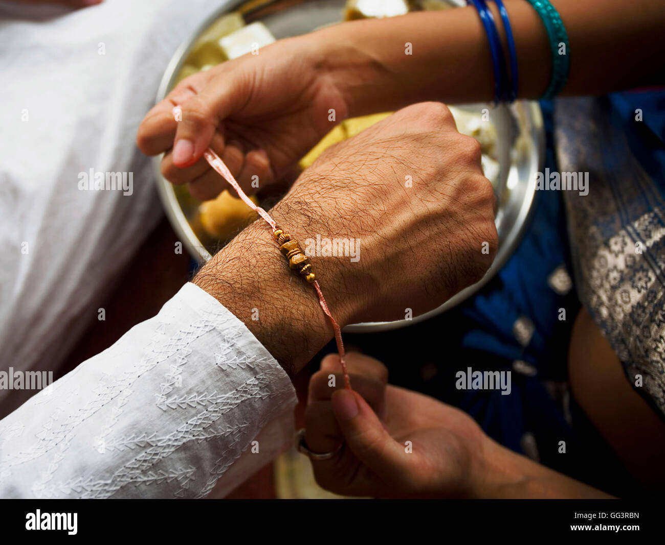 Tying a rakhi on a wrist Stock Photo - Alamy