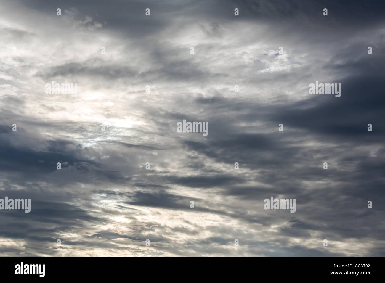 dark overcast sky with rainy clouds and the sun shining through them Stock Photo - Alamy