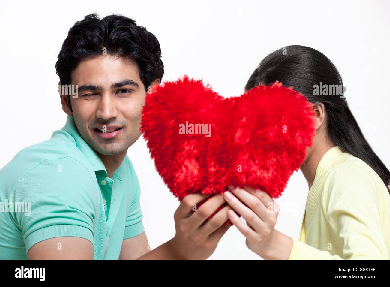 Portrait of man winking while woman hiding her face behind heart Stock ...
