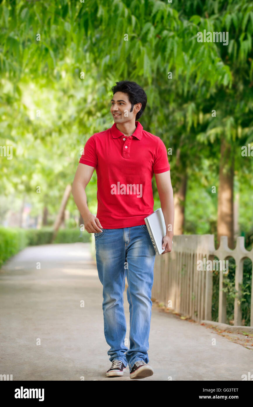 Smiling young man walking in park Stock Photo - Alamy