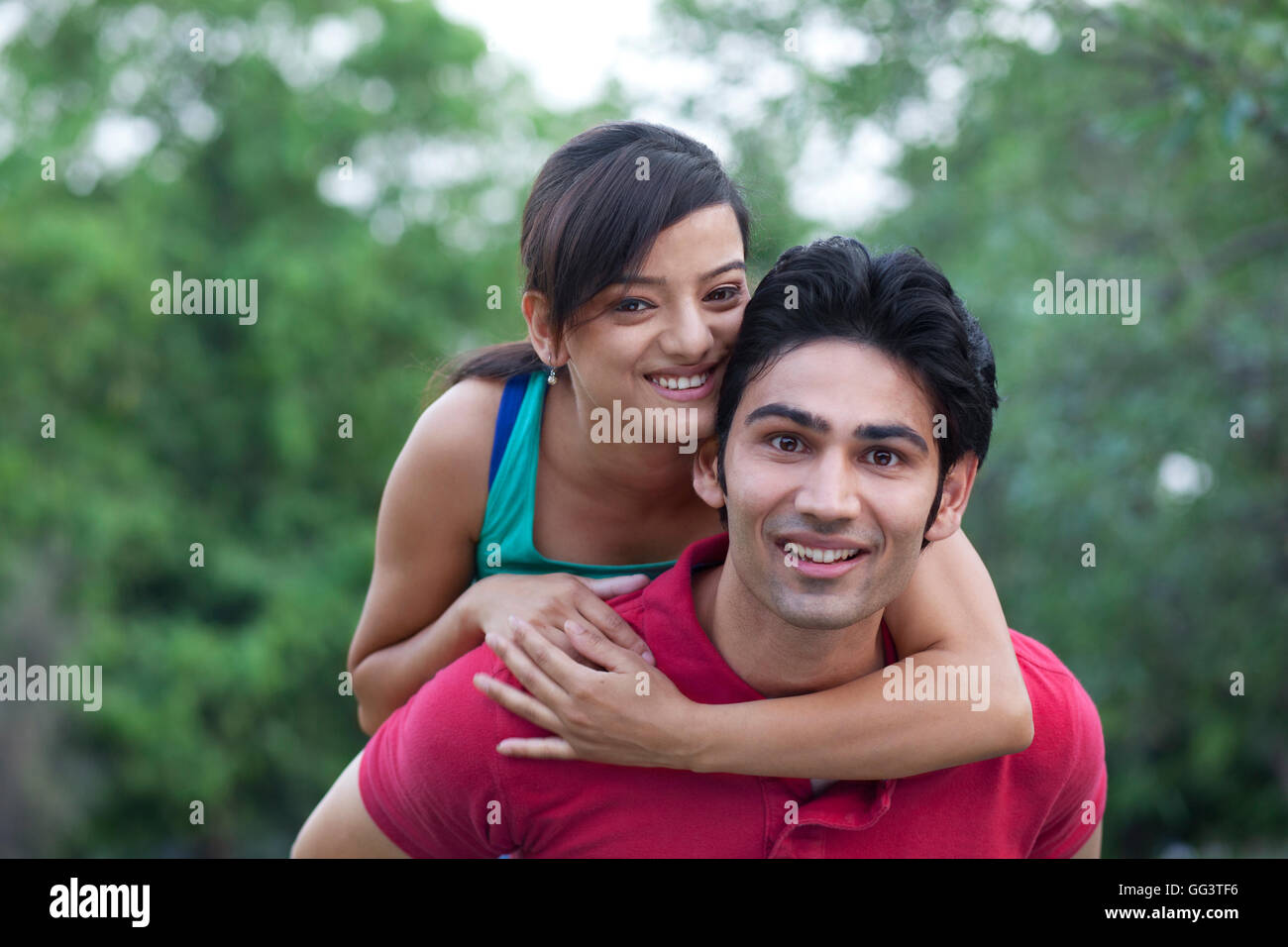 Man giving woman piggy back ride in park Stock Photo - Alamy