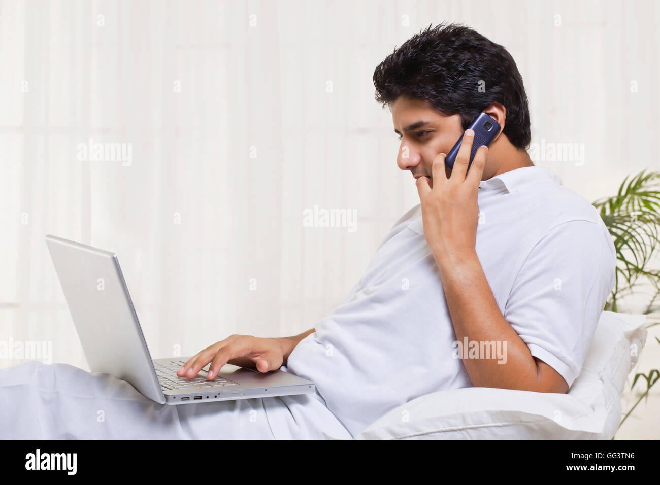 Young man having conversation while using laptop Stock Photo - Alamy