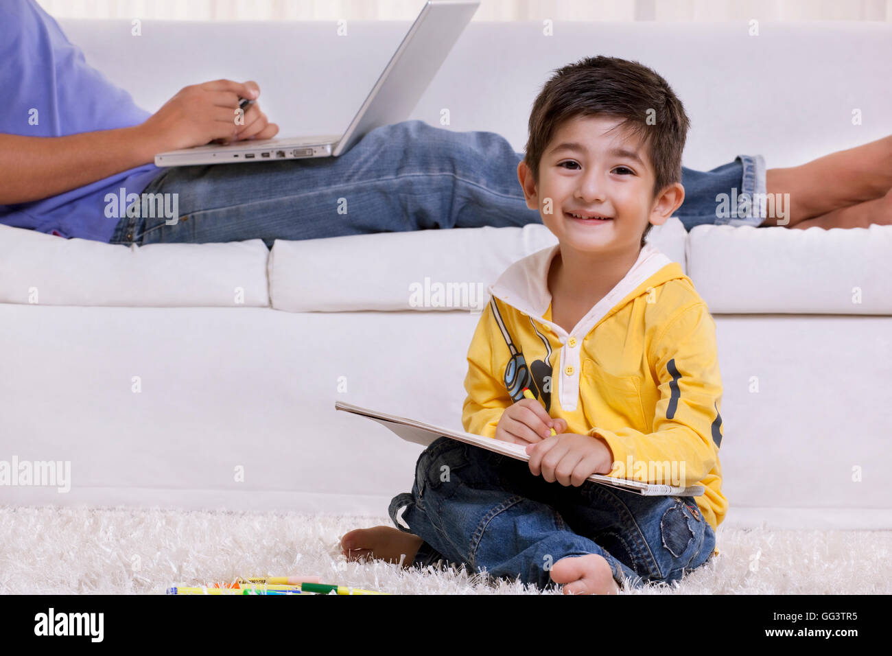Portrait of smiling boy drawing with father in the background Stock ...