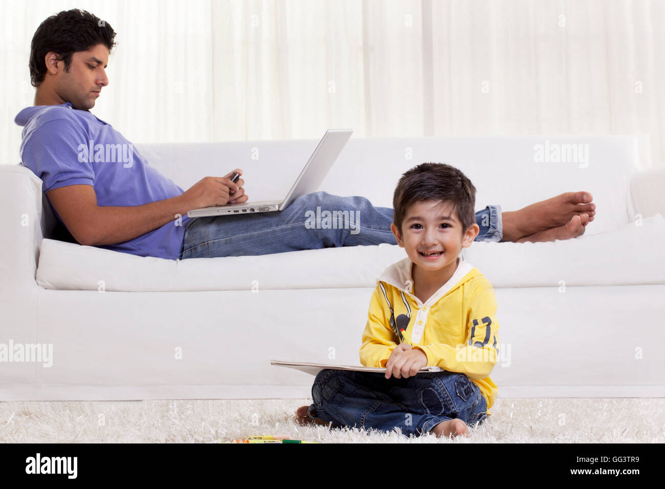 Portrait of a cute boy drawing while father texting in the background ...