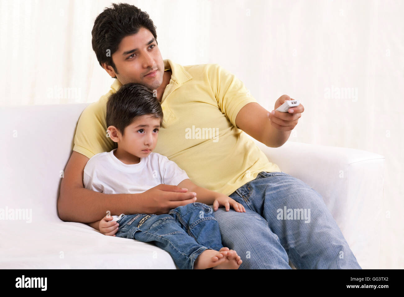 Father changing channels while sitting with his son Stock Photo - Alamy