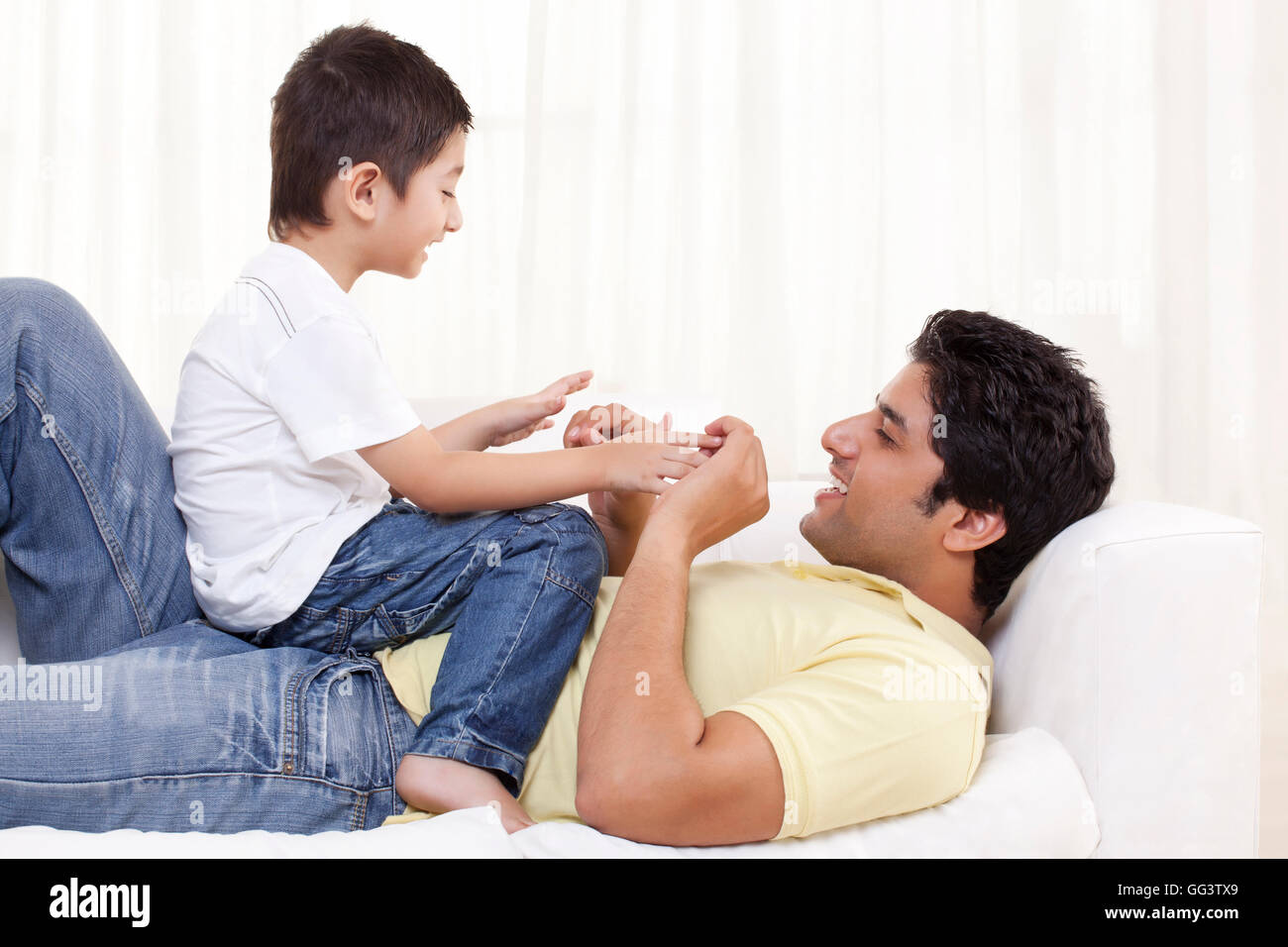 Boy sitting on father at home Stock Photo - Alamy