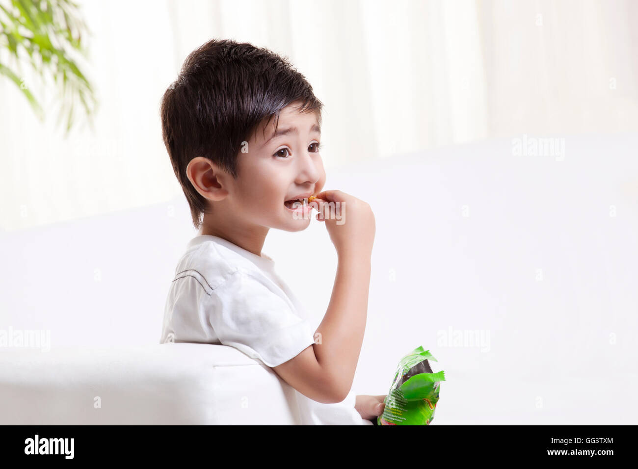 Cute little boy eating crisp Stock Photo - Alamy
