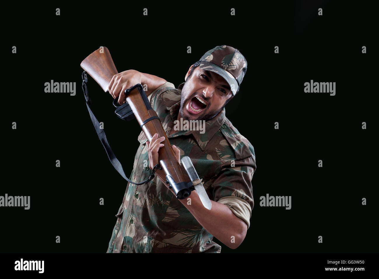 Portrait of an angry young soldier holding gun Stock Photo - Alamy
