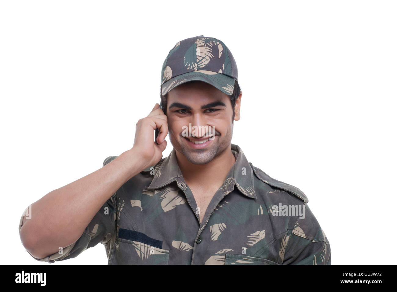 Smiling young soldier having conversation on mobile phone over white ...