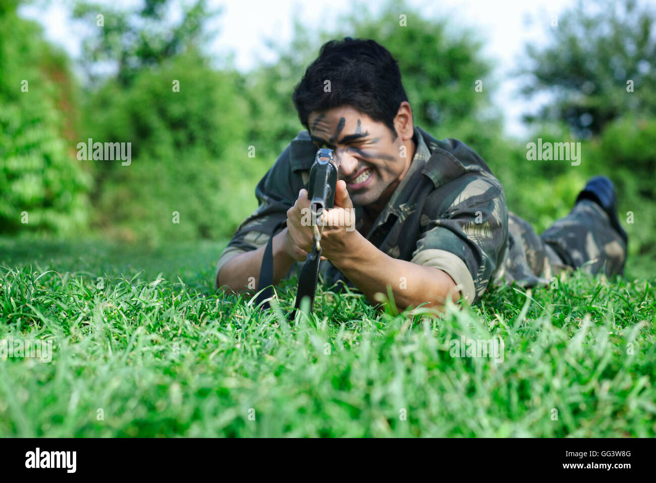 Army soldier aiming with rifle while lying on grass Stock Photo - Alamy