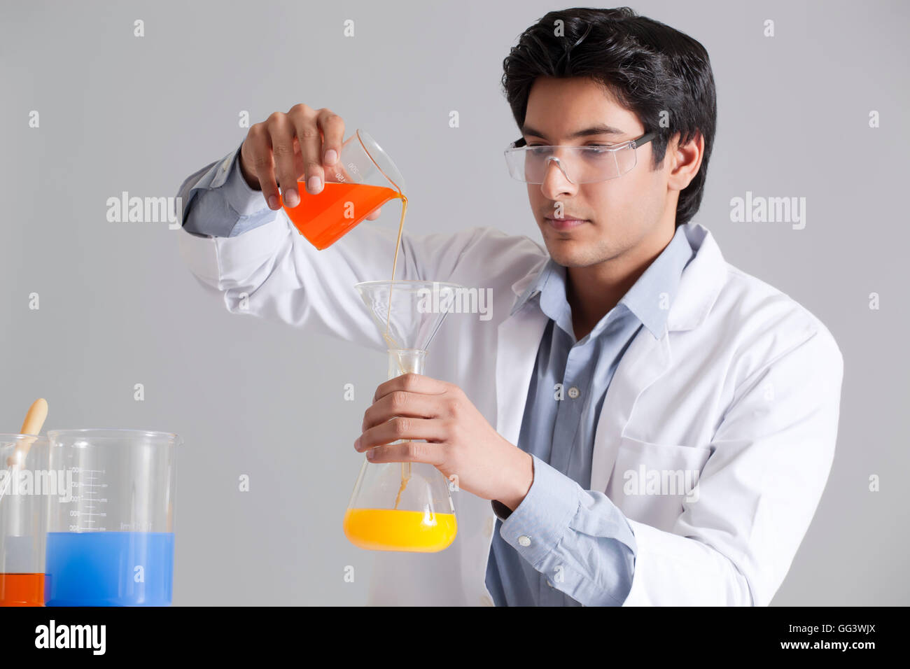 Male scientist pouring solution in a flask Stock Photo - Alamy