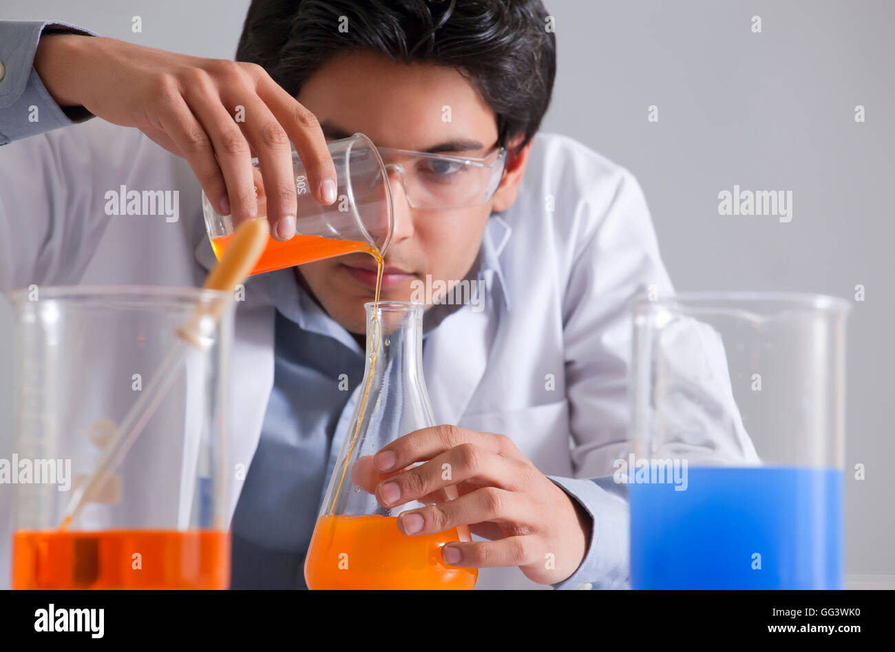 Young scientist pouring liquid into flask Stock Photo - Alamy