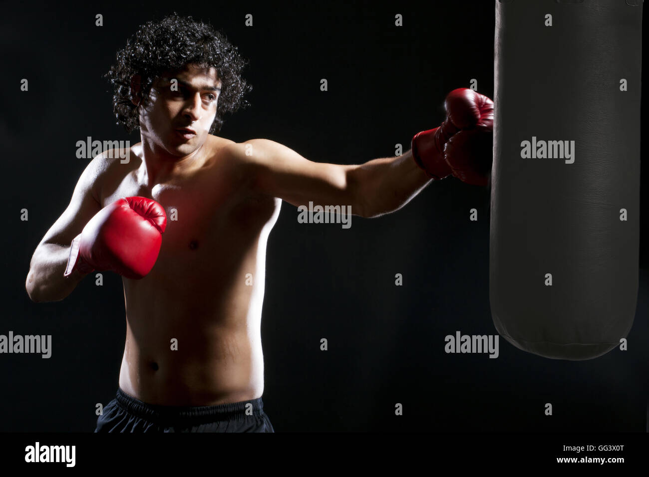 Male boxer hitting heavy bag over black background Stock Photo - Alamy
