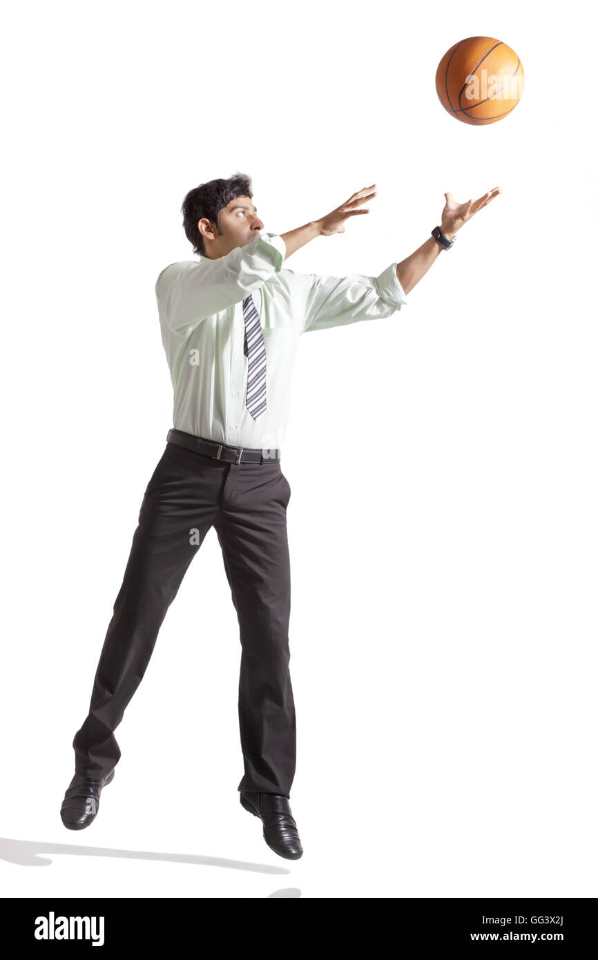 Basketball player in air preparing to dunk ball over white background ...