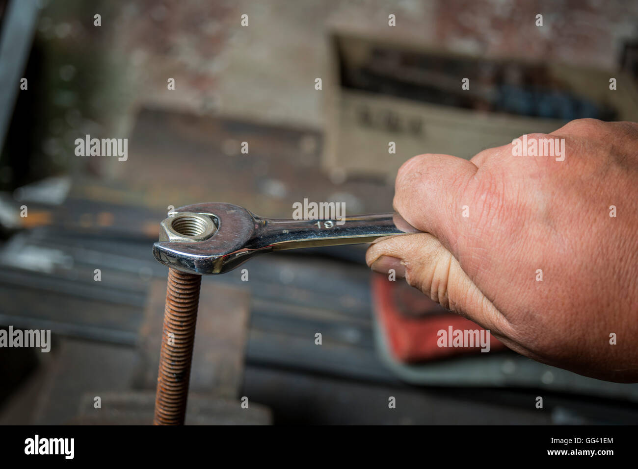 worker hand tightening or loosening a nut of a rusty bolt with a wrench ...