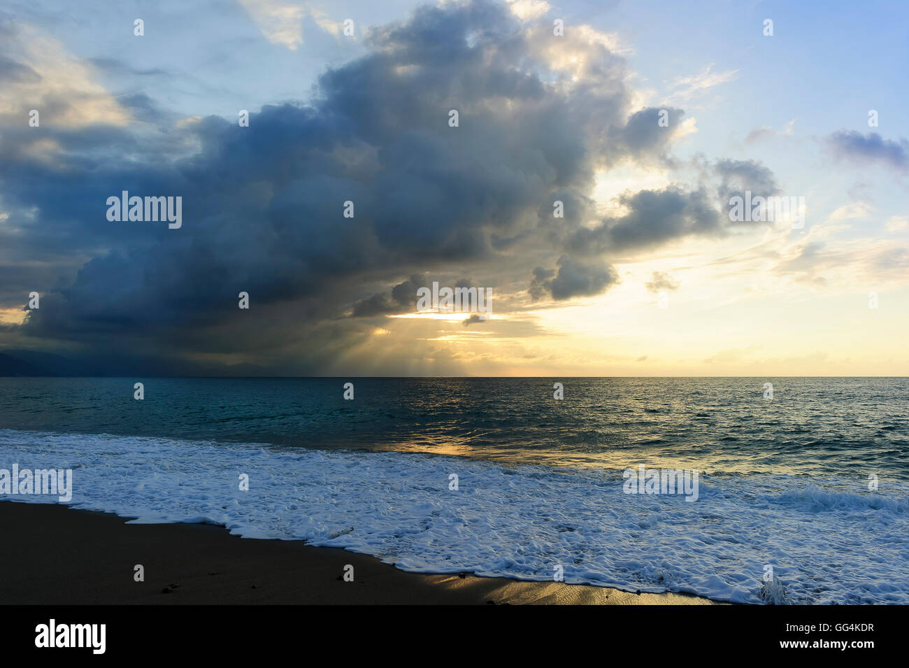 Ocean sunset sun rays is an ominous storm moving in over the ocean as a ...